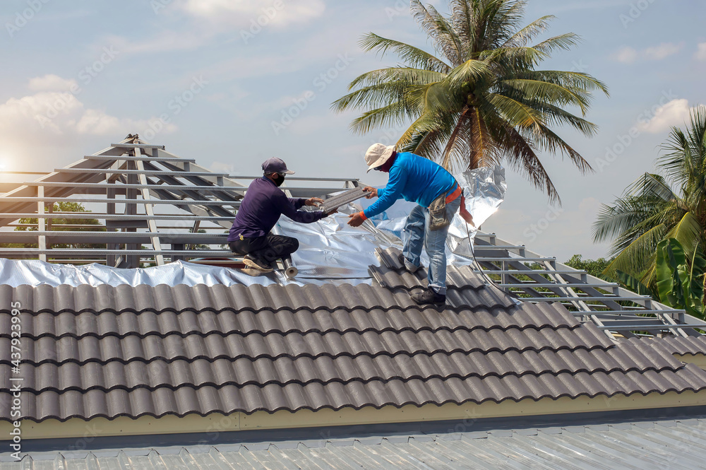 Construction workers install roof tiles on top roof, roof structure of ...