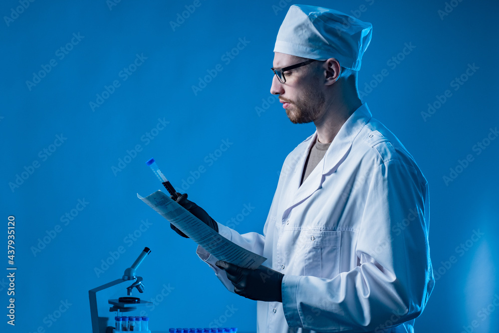 The geneticist holds a test tube of blood. A man in a doctor's uniform ...