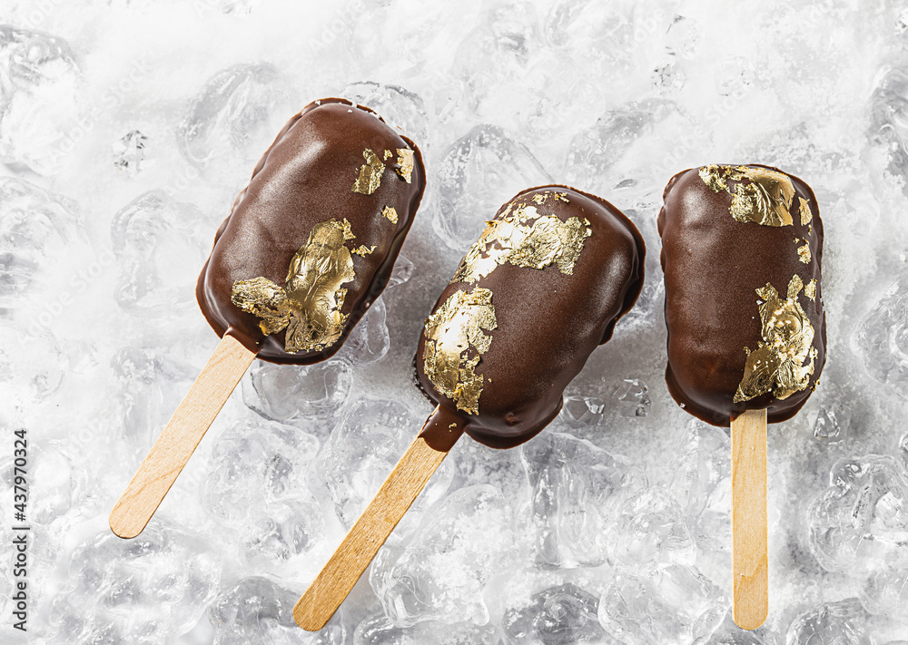 Popsicles, covered with chocolate, with a leaf of edible gold on top on ...