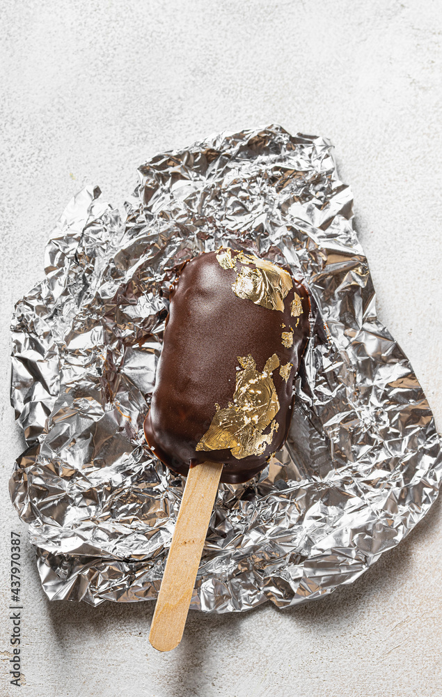 Popsicles, covered with chocolate, with a leaf of edible gold on top on ...