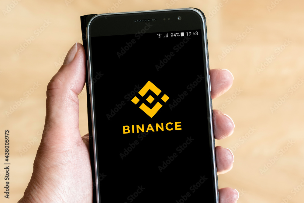 Main de femme tenant un téléphone portable avec le logo de Binance ...