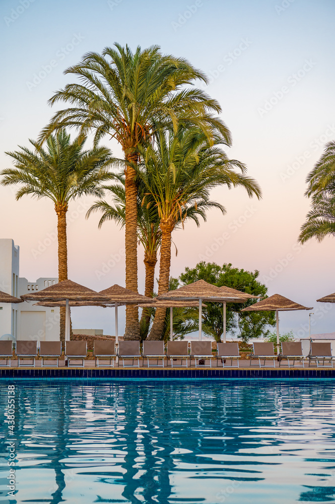 Beautiful sunset at a beach resort in tropics. Tropical swimming pool ...