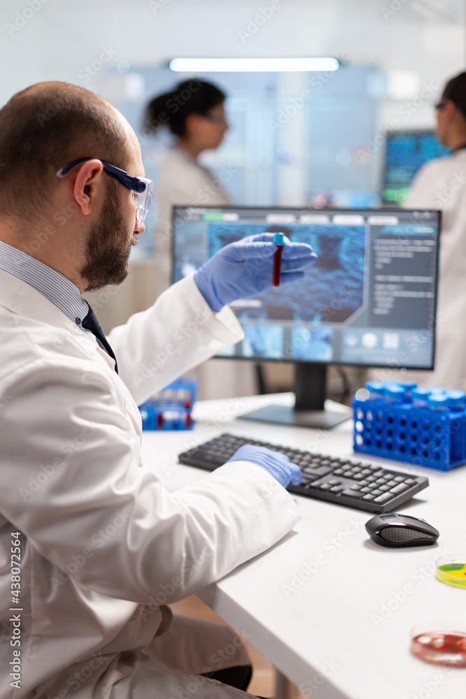 Genetic scientist studying epidemics holding sample of blood in test ...