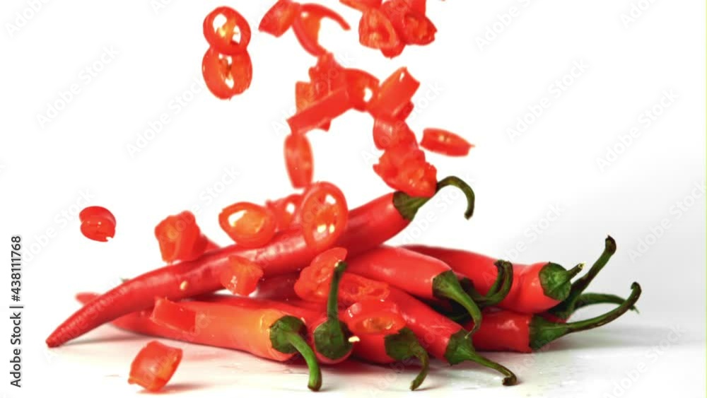Super slow motion pieces of chili pepper fall on a bunch of pepper pods ...