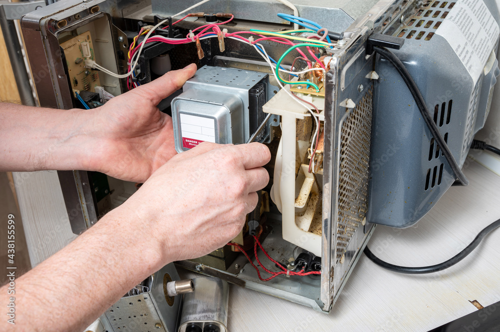 Repair of the microwave oven. A men replaces a magnetron. Stock Photo ...