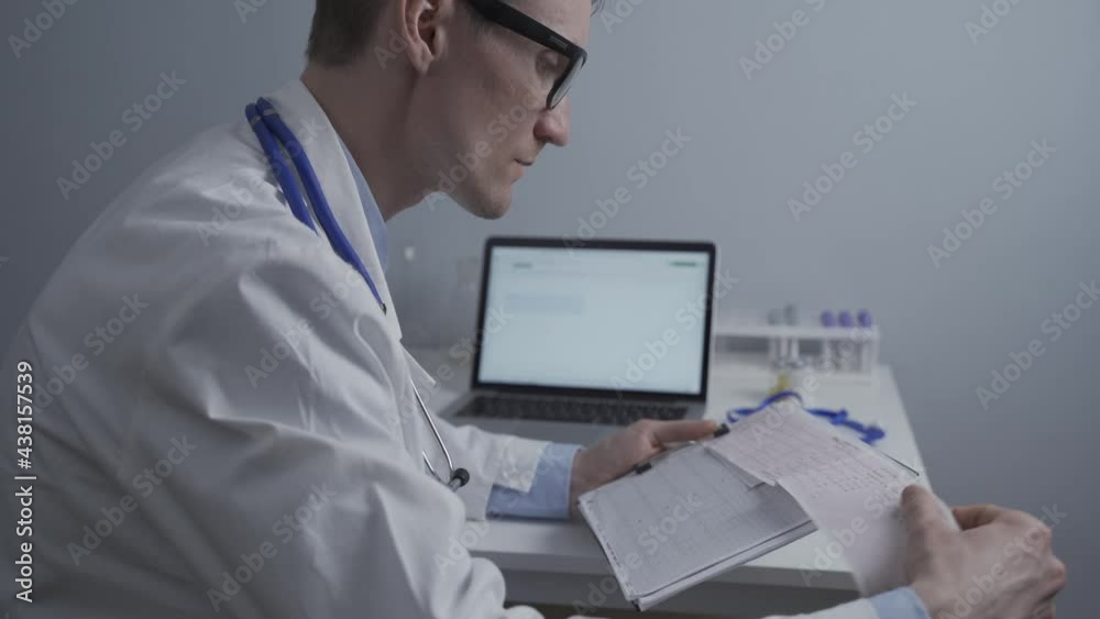 Cardiologist reading an ECG print-out. Doctor analyzing ...