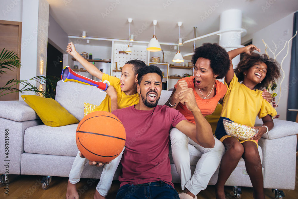 Happy African American family watching tv and cheering basketball games on sofa at home. Stock ...