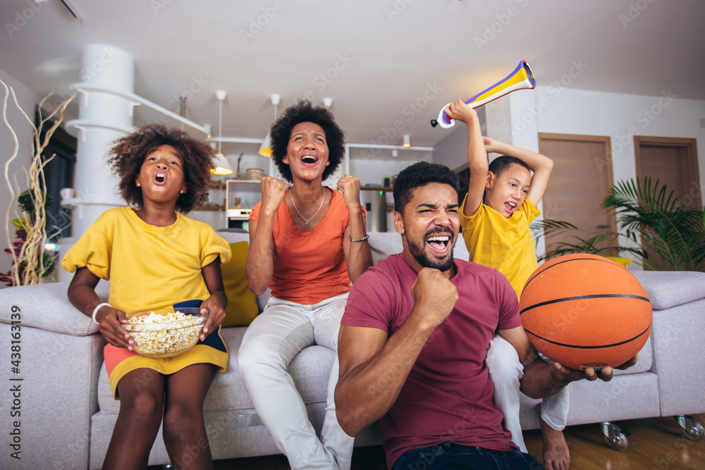 Happy African American family watching tv and cheering basketball games on sofa at home. Stock ...