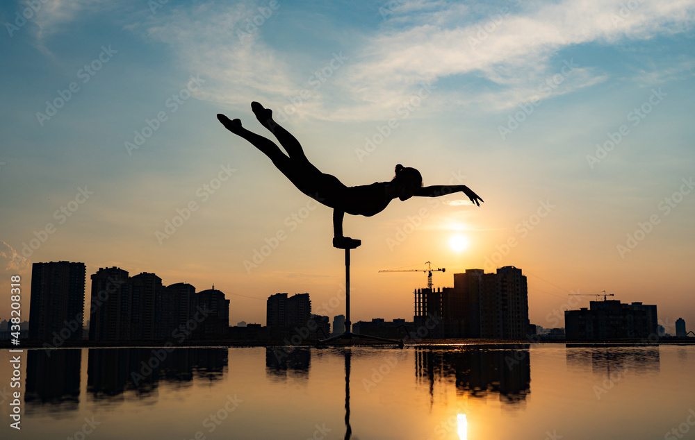 Flexible acrobat doing handstand on the cityscape background during ...