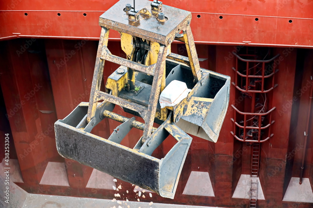 Loading bulk cargo of limestone from barges into a bulk carrier by ...