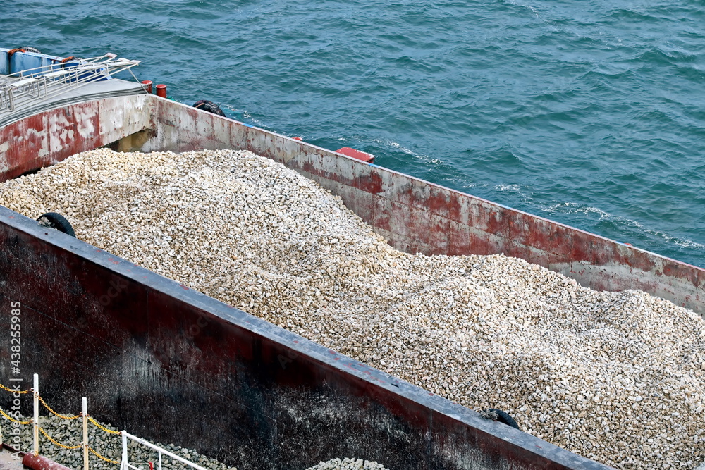 Loading bulk cargo of limestone from barges into a bulk carrier by ... Loading bulk cargo of limestone from barges into a bulk carrier by ...