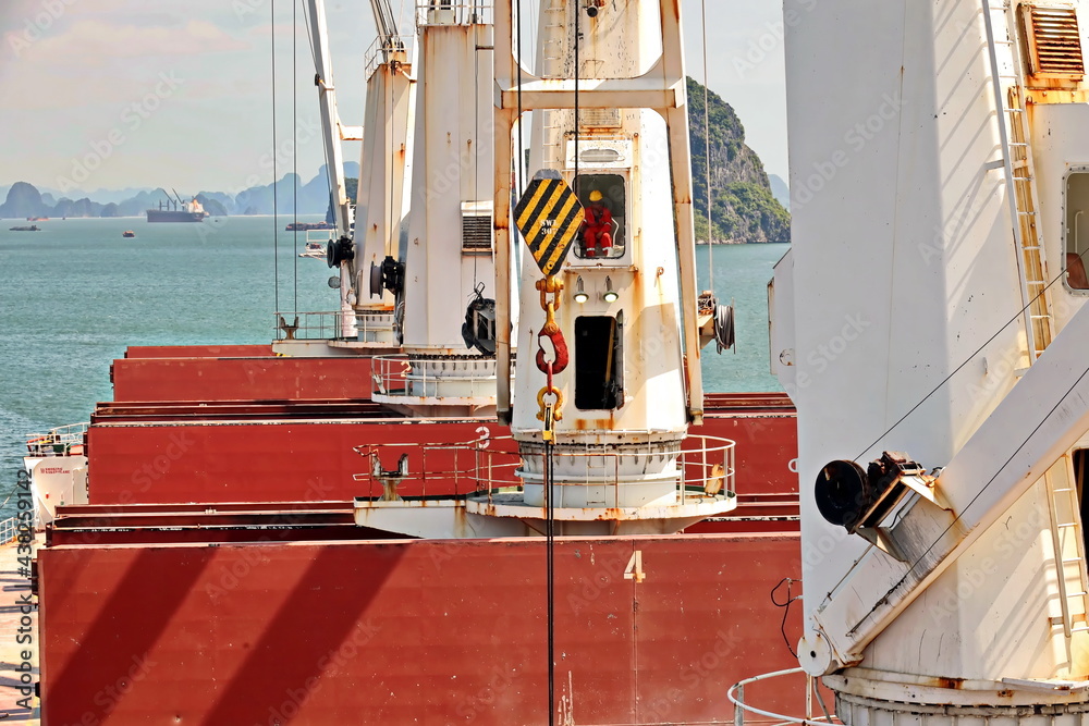 Loading bulk cargo of limestone from barges into a bulk carrier by ...
