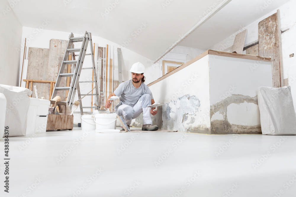 plasterer man at work, take the mortar from the bucket with trowel to ...
