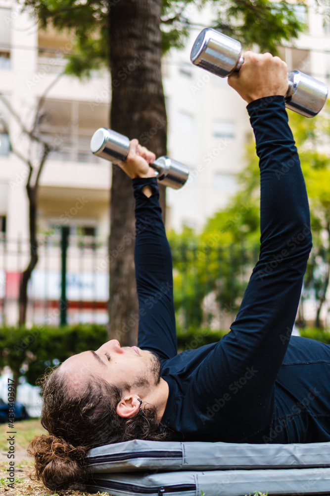 upright photo of a long-haired Brazilian man lifting metal weights ...
