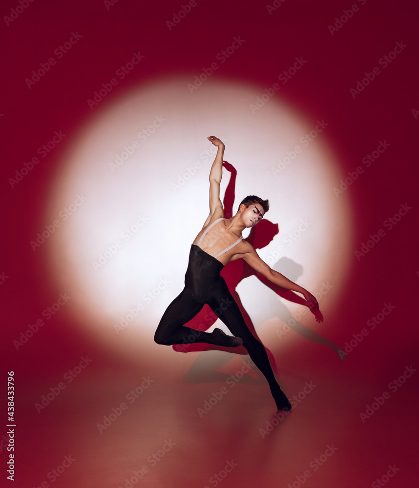 Ballet dancer dancing over red studio background. Modern design ...