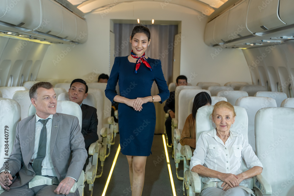 Portrait of cabin crew or air hostess in economy class cabin smiling to ...