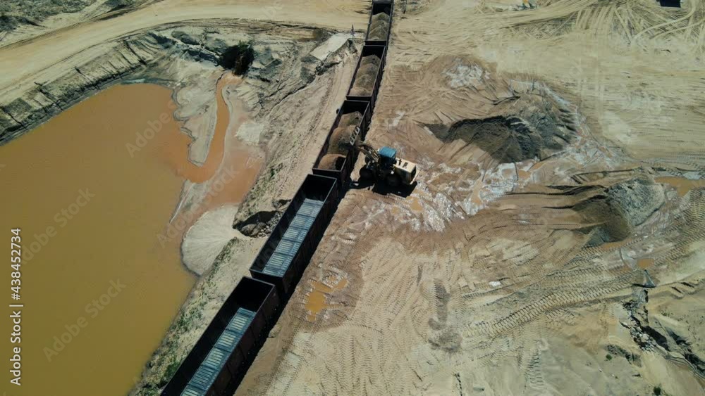 Front-end loader loading sand it to the freight train. Mining work in a ...