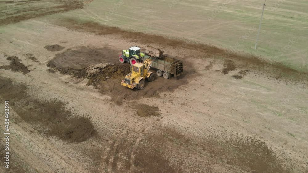 Front loader fills the tractor's trailer spreader with smelly manure ...