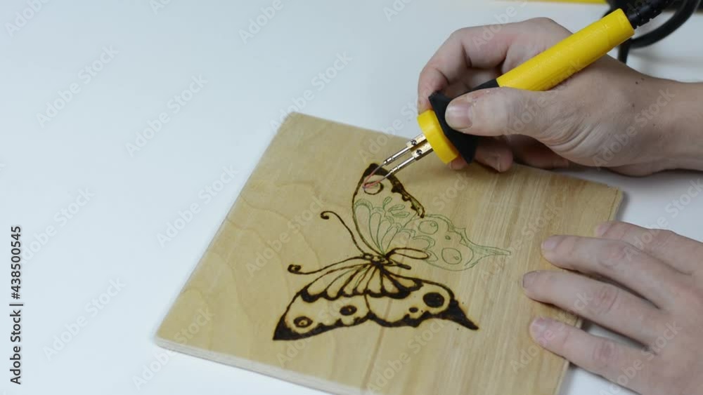 Drawing a picture on a tree using a burning device. A man's hand holds ...