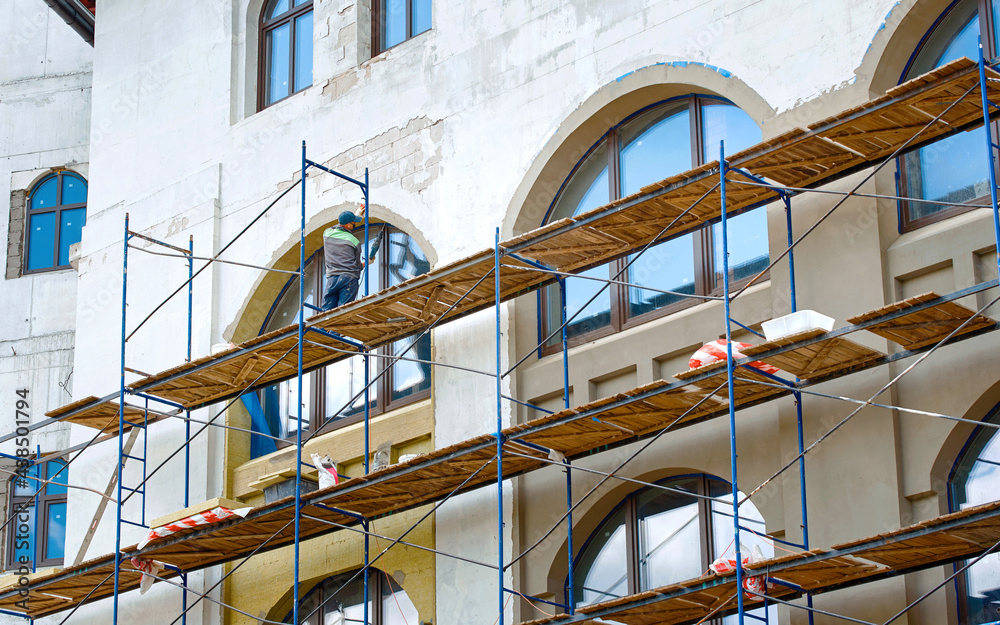 Facade insulation of new building. Scaffolding. Construction worker ...