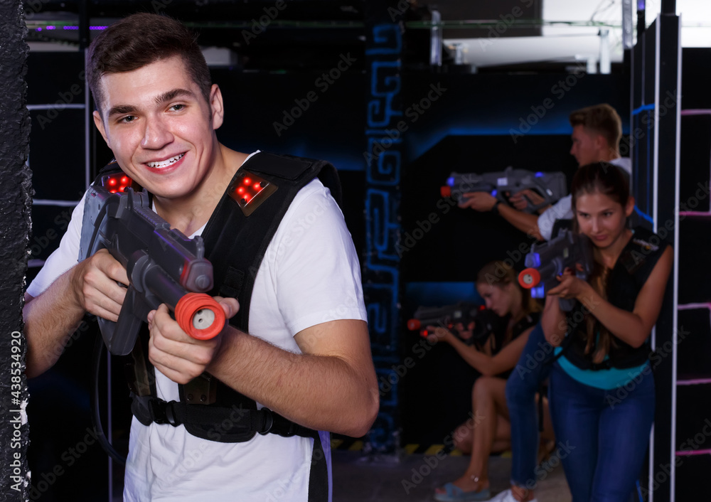 Excited guy holding laser pistol and playing laser tag with his friends ...