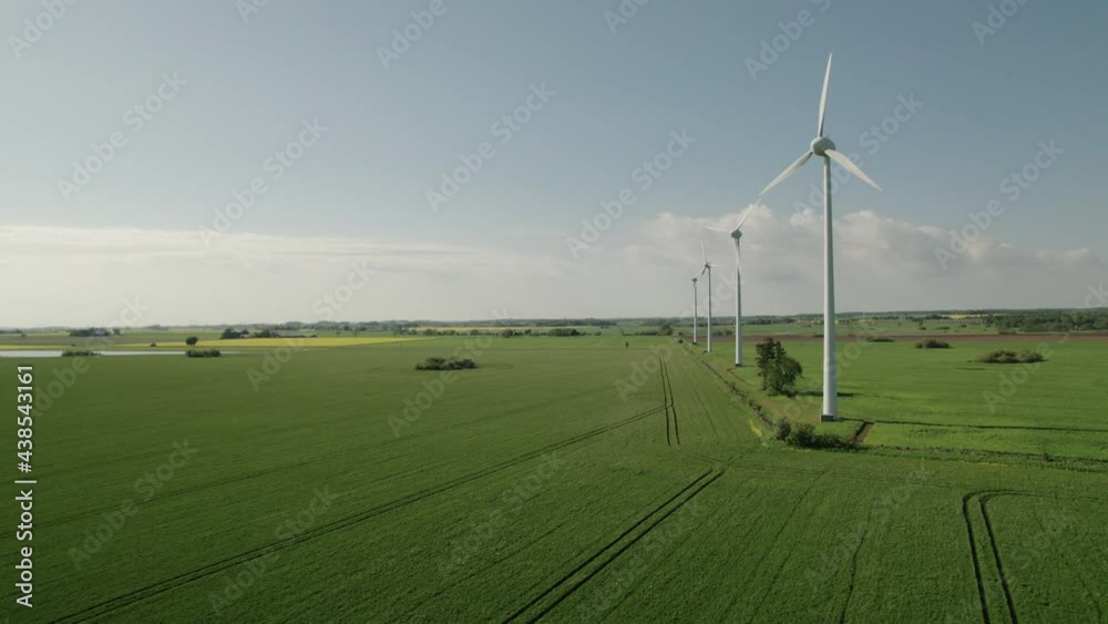 Row of giant windmill turbines spinning on a organic farm field, Skåne ...