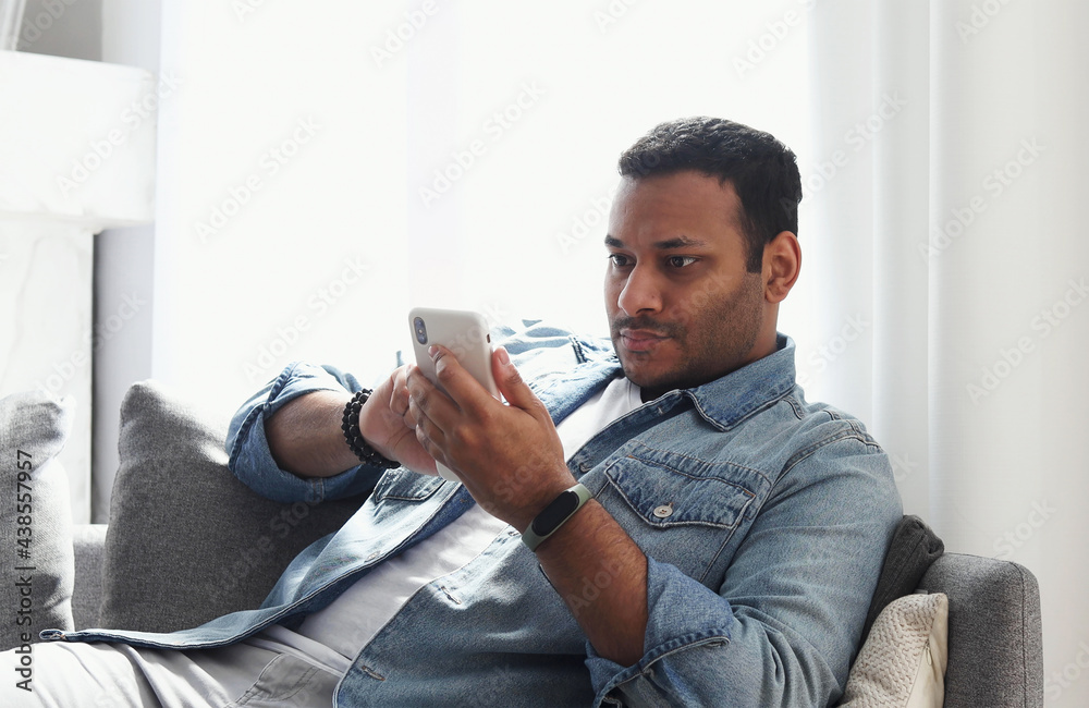 Young indian man using mobile phone to search the internet for goods ...