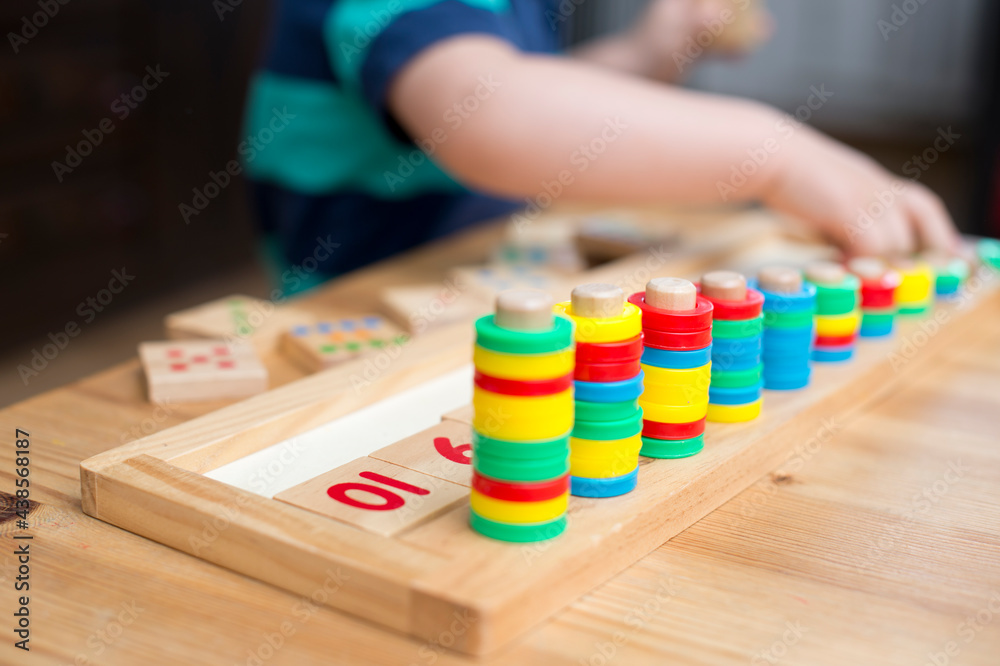 infant child playing with different color wooden rings. engaged baby ...