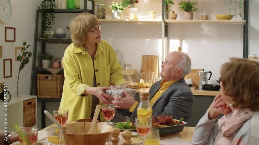 Joyous senior woman giving gift box, saying wishes and embracing ...