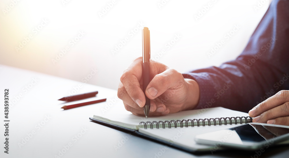 Businessman hand holding writing pen memo into notebook paper on table ...