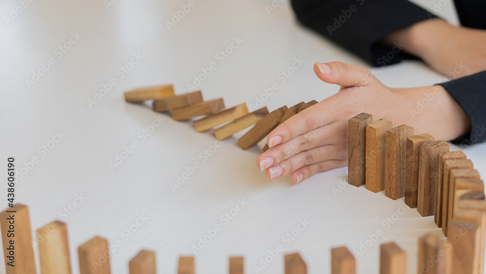 risk control concept A businessman defends a falling wooden block and a ...