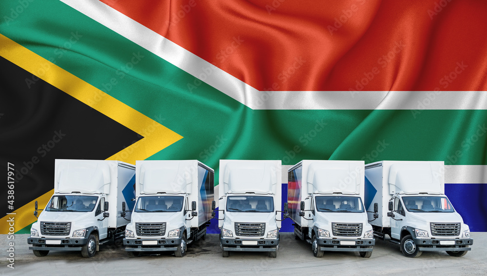 South Africa flag in the background. Five new white trucks are parked ...