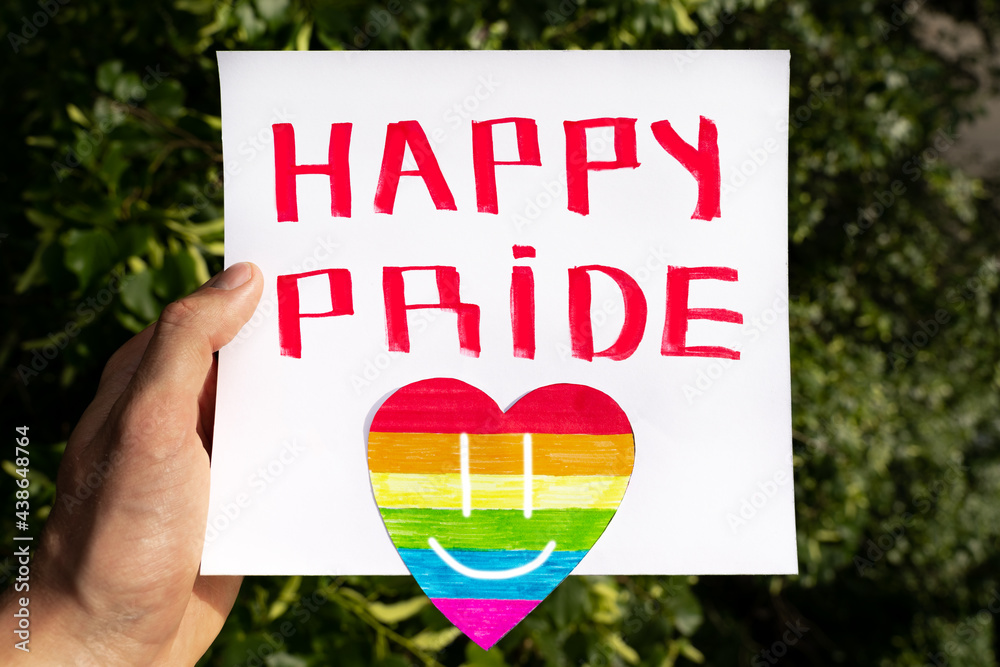 hand holds happy pride inscription on the placard with rainbow heart in ...