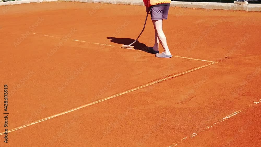 Tennis court maintenance with a linear brush. Cleaning the lines on the ...