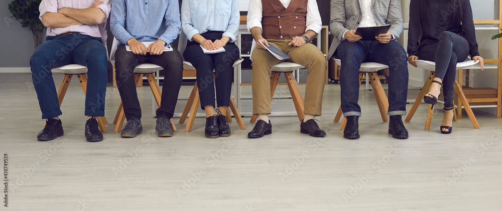Group of business people sitting on chairs in modern office, legs and ...