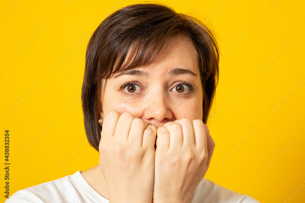 Scared woman keeps hands on cheeks, looks with surprisement and fear at ...