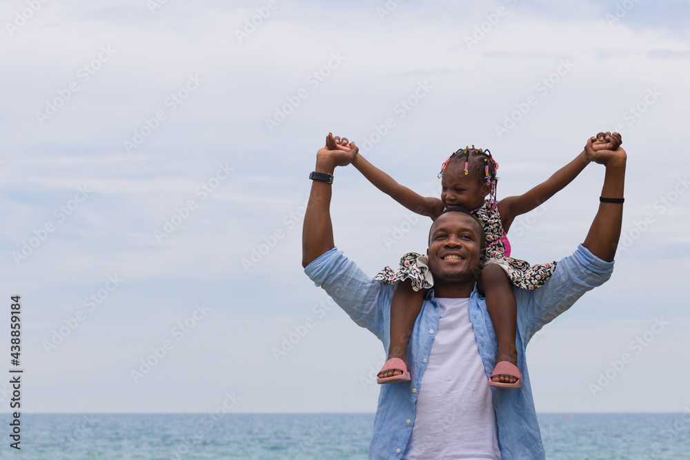 Happy father carrying daughter on shoulders at beach, Cheerful african american girl on the ...