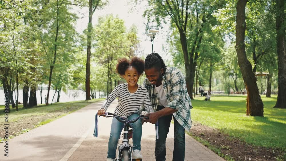 Close up portrait of father teaches his daughter to ride a two-wheeled ...