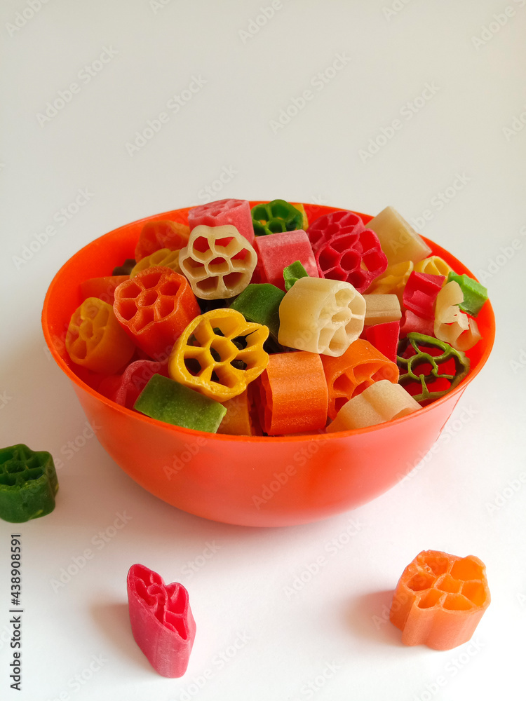 Side view of raw fryums in an orange bowl in isolated white background ...