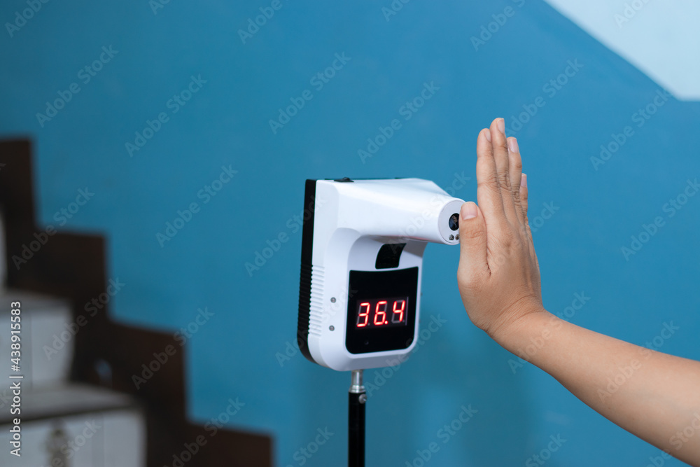 Hands of a woman measuring body temperature with an infrared ...