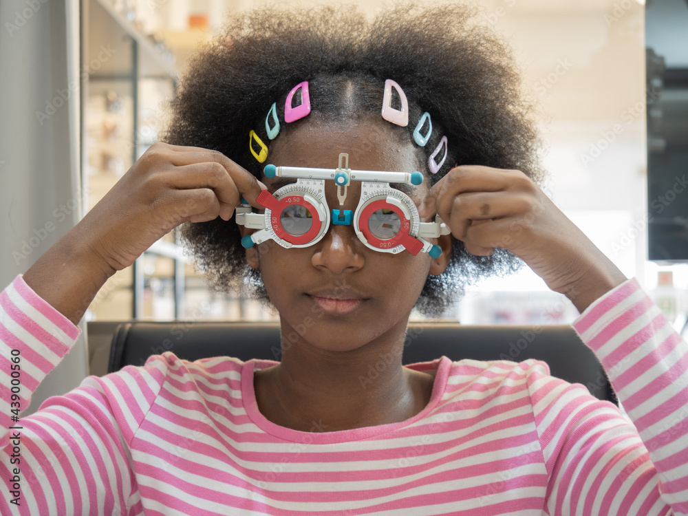 African girl putting optical trial frame to determine visual acuity ...