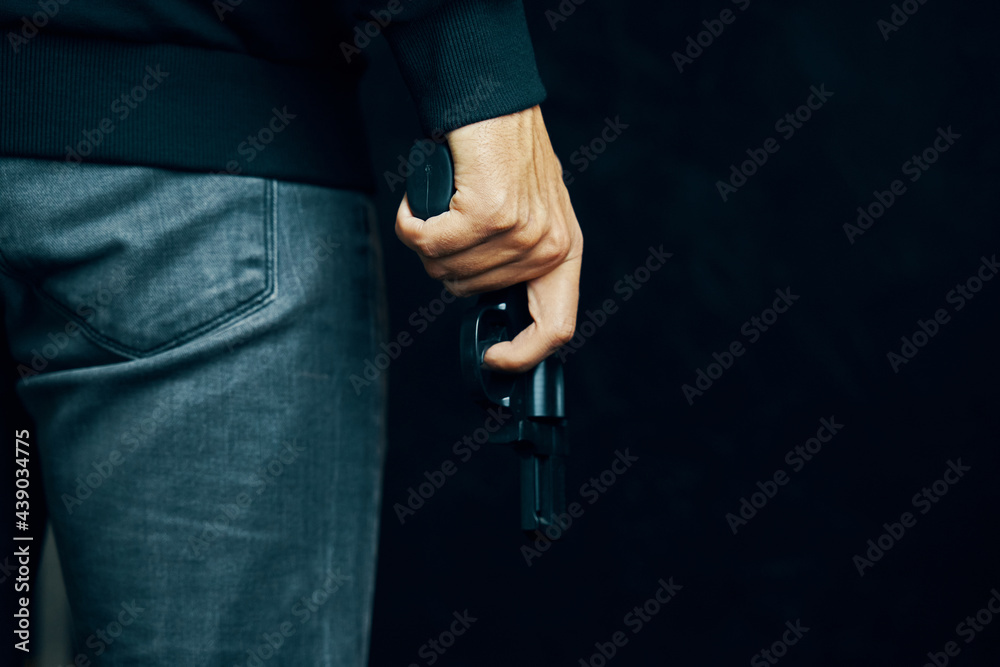 Dangerous pistol in person hand. Man in sweater and jeans is holding ...