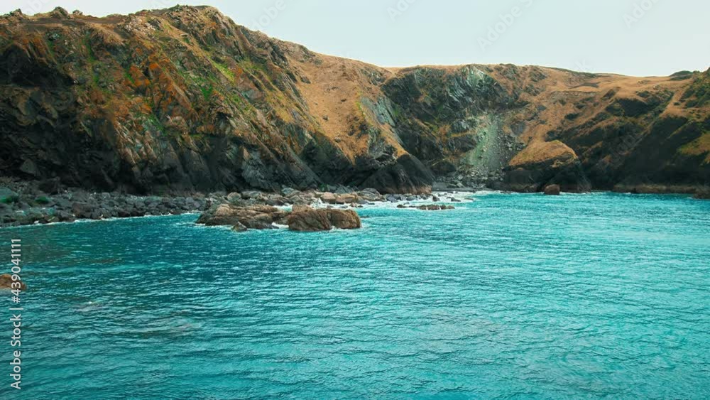 A seashore with big rocks formation, cliffs and blue waters from the ...