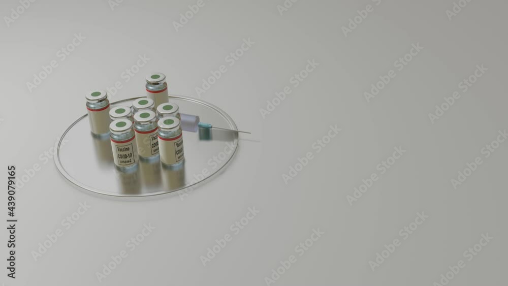 Covid 19 vaccine jars and a disposable plastic syringe rotate on a ...