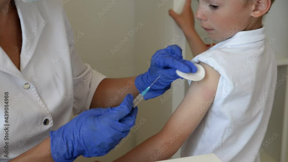 Doctor giving an injection to a child against coronavirus (flu). The ...