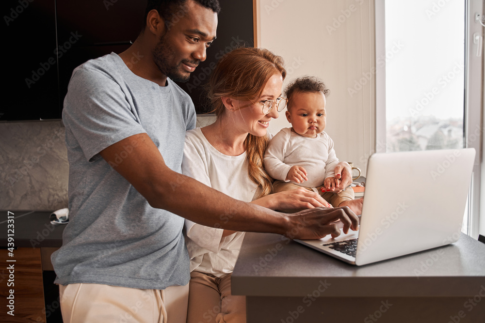 Family looking at the laptop screen while their child sitting Stock ...