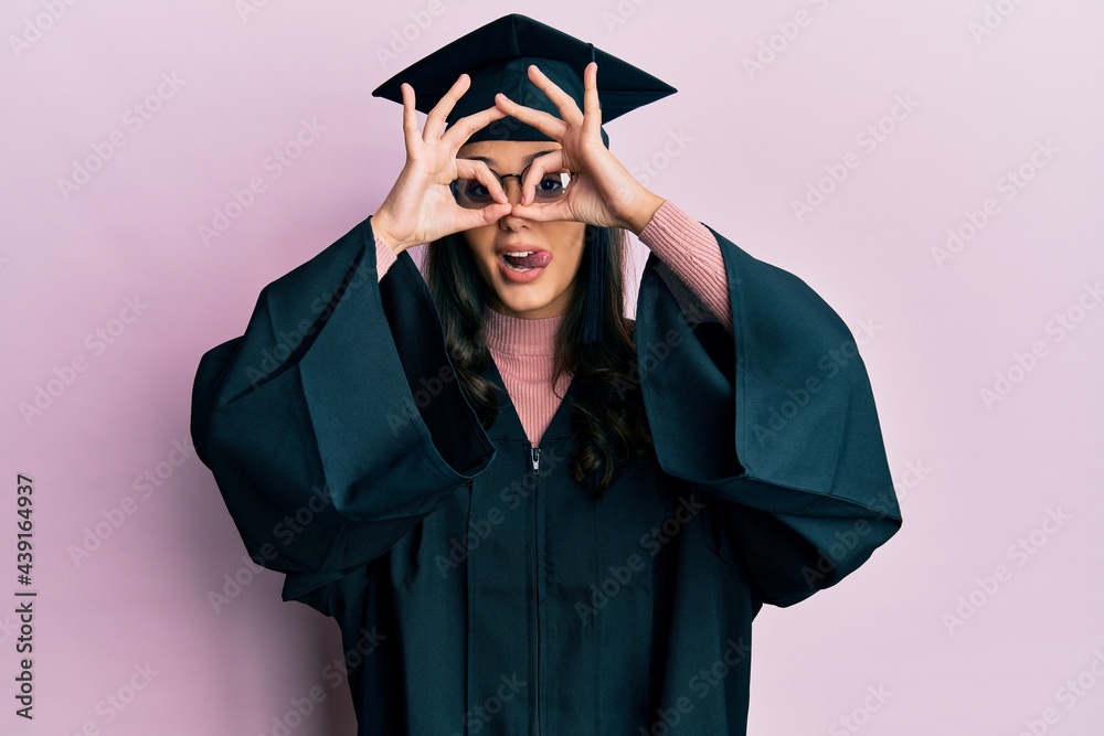 Young hispanic woman wearing graduation cap and ceremony robe doing ok ... Young hispanic woman wearing graduation cap and ceremony robe doing ok ...