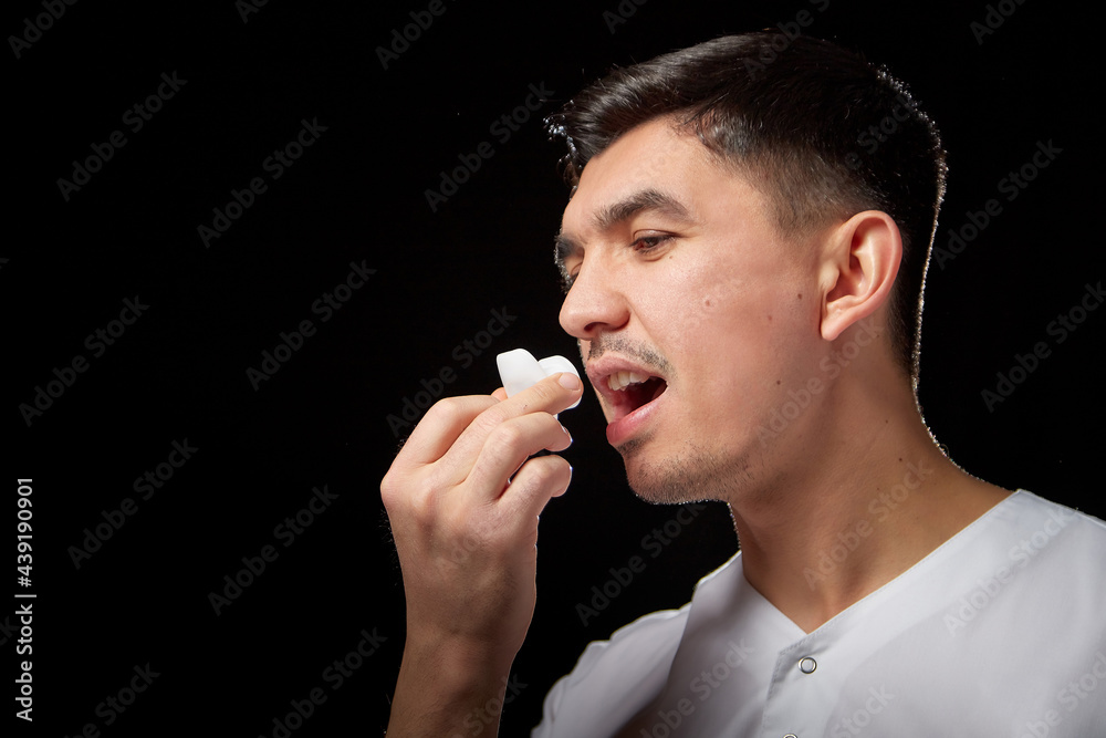 A young man who is a medical doctor in a white uniform poses against a ...