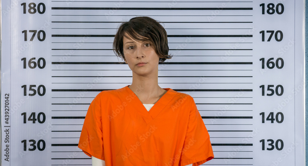 Arrested young woman posing in an orange suit for a mugshot Stock Photo ...