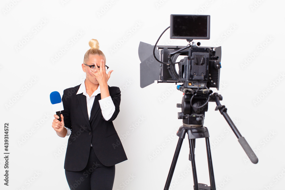 pretty blond woman looking shocked, scared or terrified, covering face ...